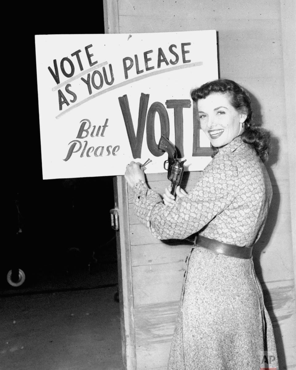 Actress Jane Russell nails a voting sign to a sound stage door with a ...